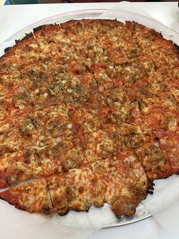 Behold the legendary tavern-style sausage pizza—thin enough to eat three slices but substantial enough to remember for years.