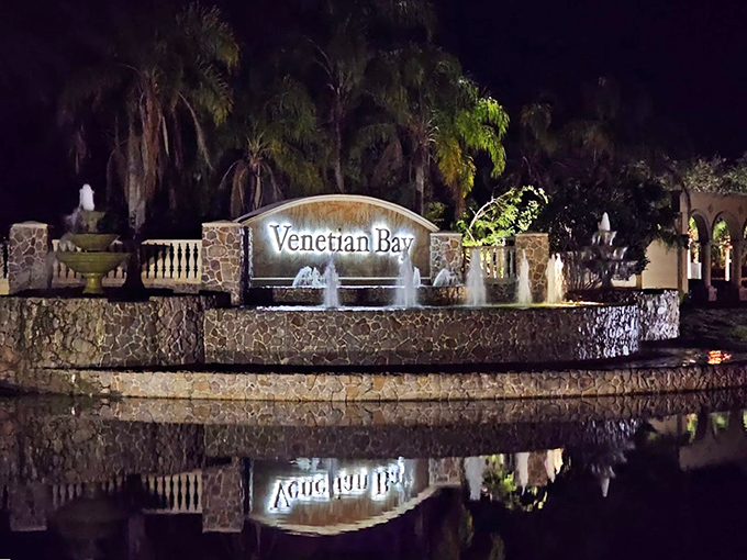 Nighttime transforms the entrance fountain into a magical oasis, its illuminated waters reflecting the community's name like liquid gold.