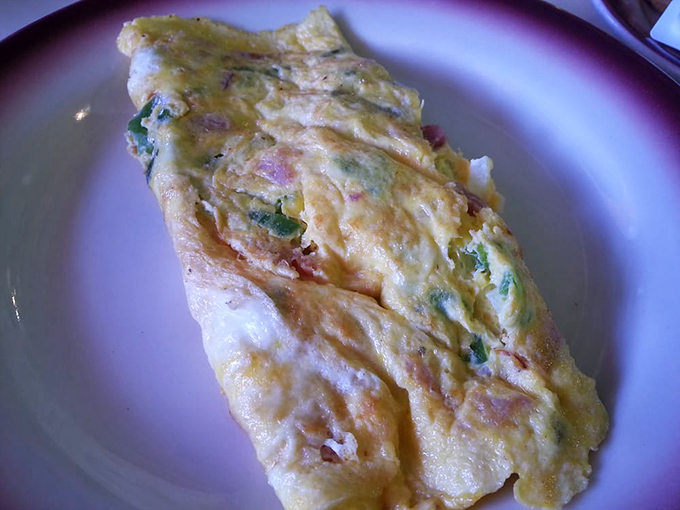 This Western omelet doesn't just contain ingredients—it embraces them in a fluffy egg blanket that's been perfected over decades of morning service.
