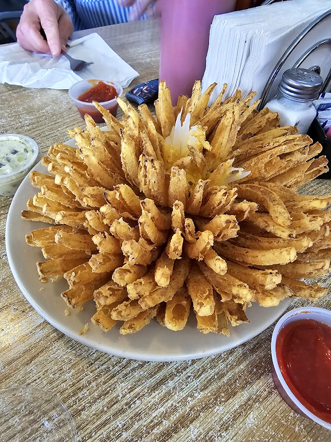 The blooming onion arrives like an edible firework display – crispy, golden petals radiating from the center, ready for their dipping sauce destiny.