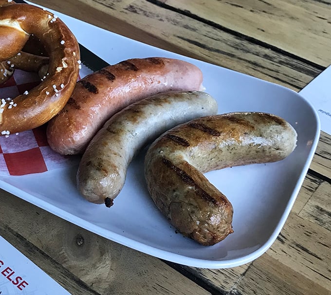 A trio of sausages with a fresh pretzel—the kind of plate that makes you wonder why you ever bothered with those sad boiled hot dogs.