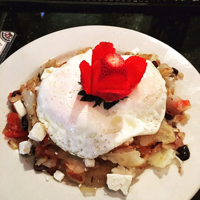 Breakfast architecture at its finest—a sunny-side-up egg crowning a foundation of savory potatoes. That strawberry "flower" is showing off.