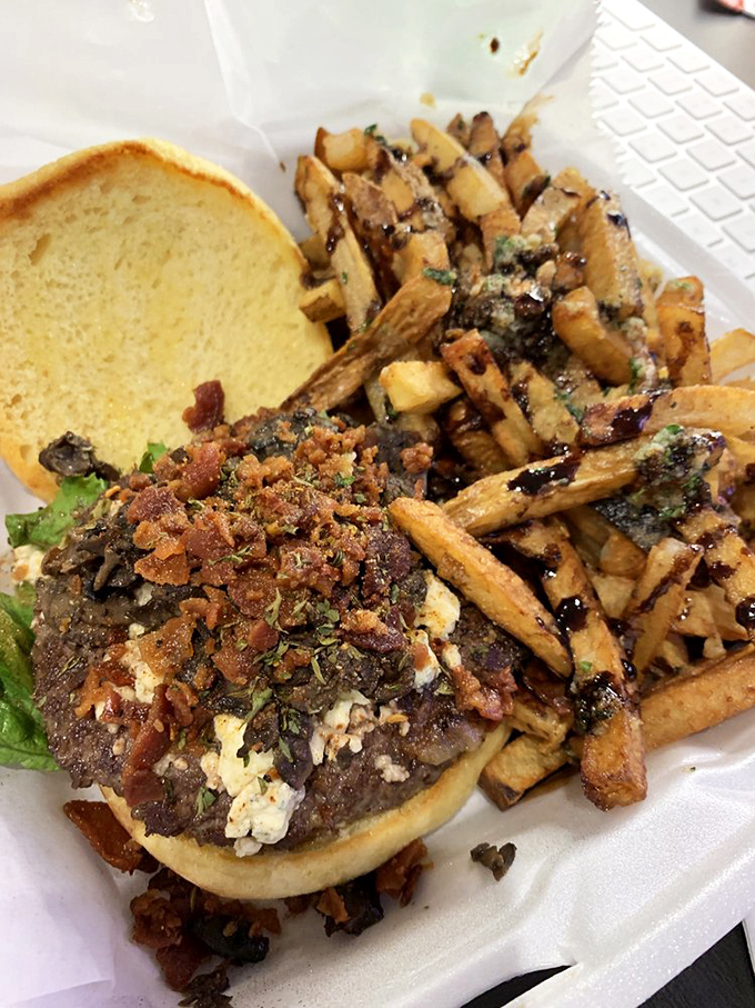 A burger masterpiece topped with bacon and blue cheese sits beside hand-cut fries – a duo more perfect than Batman and Robin.
