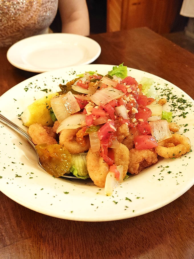 Crispy calamari topped with fresh tomato and onion—proof that sometimes the best things in life come in crispy, golden packages with a squeeze of lemon.