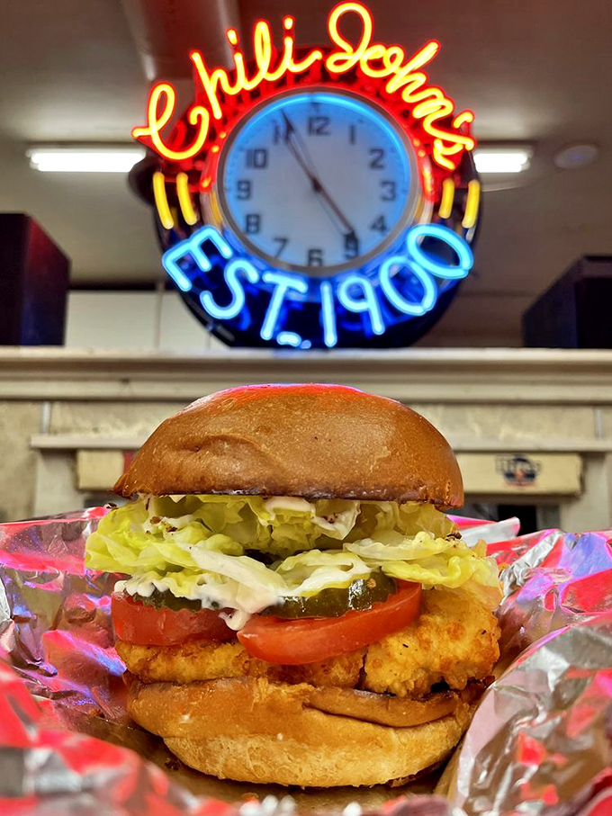 Even the chicken sandwich knows its role at Chili John's—honest comfort food served under the glow of that iconic neon clock.