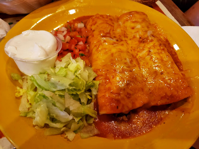 Behold the chimichanga in its natural habitat—crispy on the outside, tender within, and swimming in a vibrant sauce that demands to be sopped up.