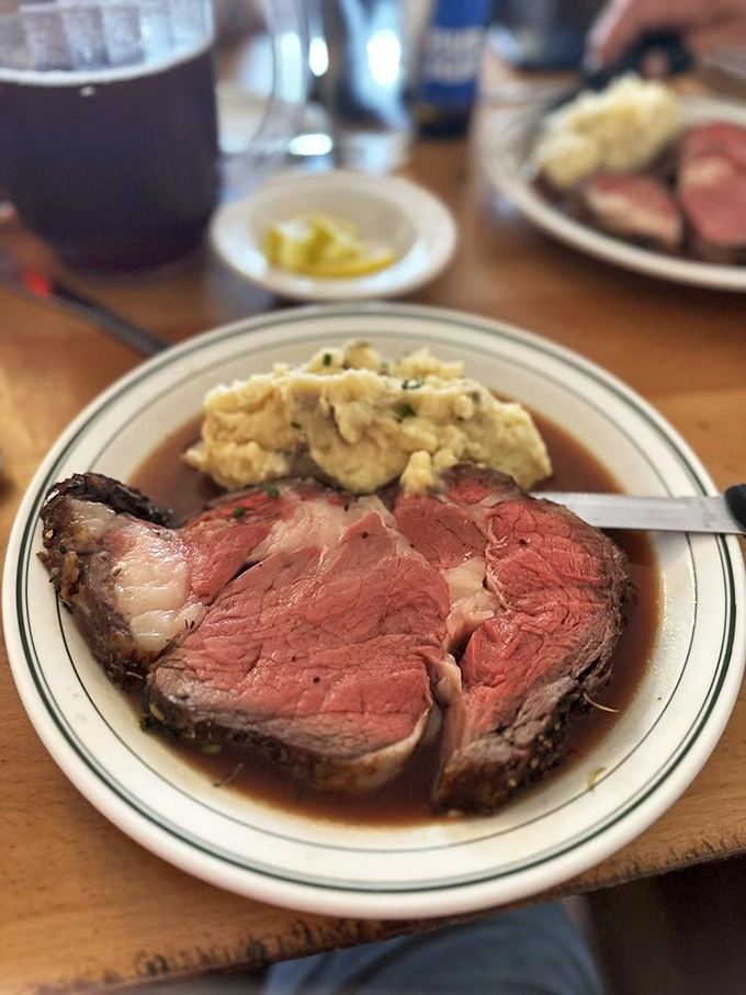 The prime rib arrives like a work of art—perfectly pink, swimming in savory au jus, with mashed potatoes standing by for gravy-soaking duty.