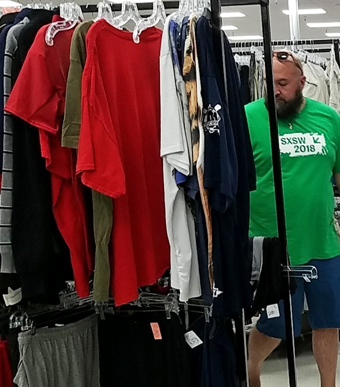Serious thrifters develop a sixth sense—this shopper's focused expression says he's hunting something specific among the rainbow of options.