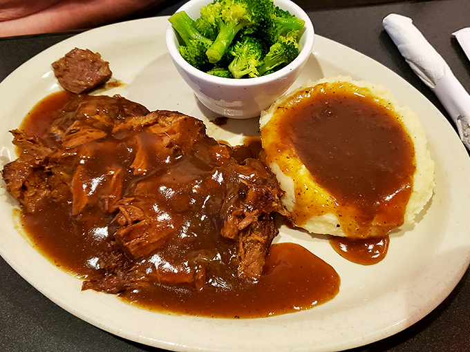 Behold the legendary pot roast in all its glory—fork-tender beef swimming in gravy that should be declared a state treasure. 