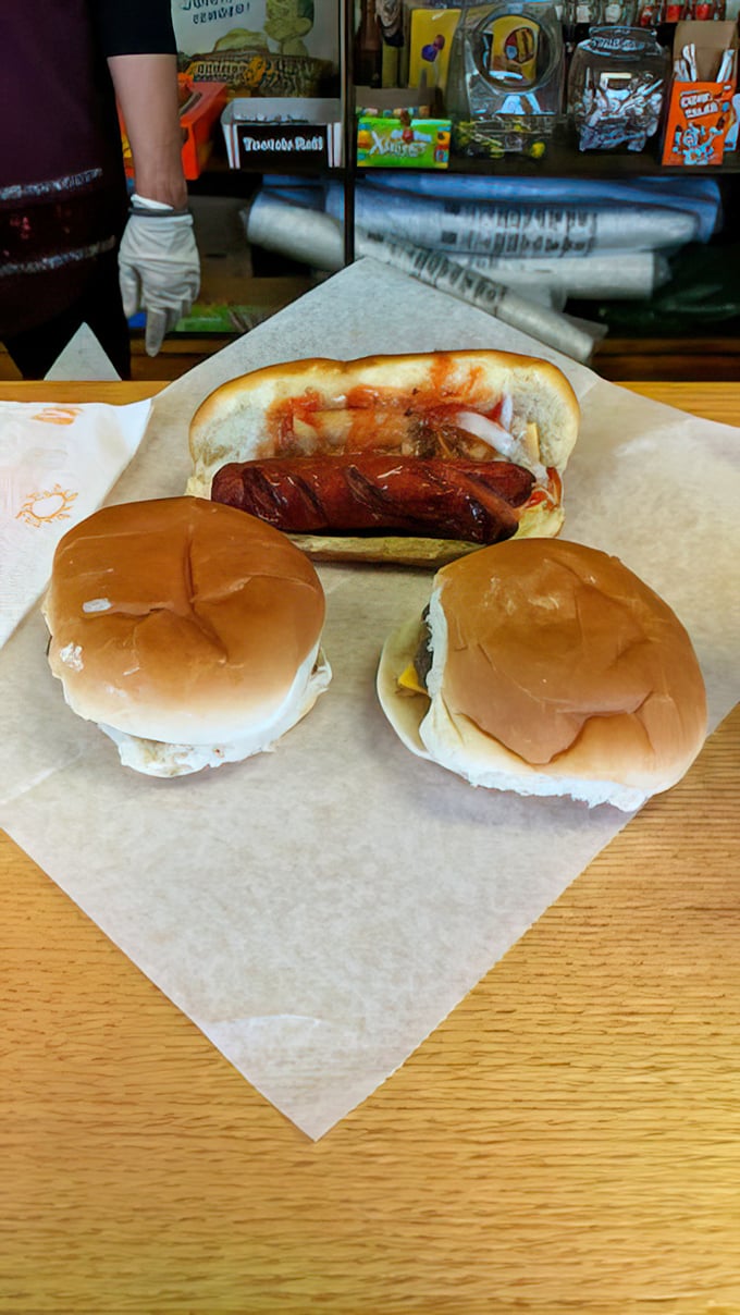 The perfect trio – two sliders and a hot dog, arranged on parchment like a still life painting that's about to become a delicious memory.