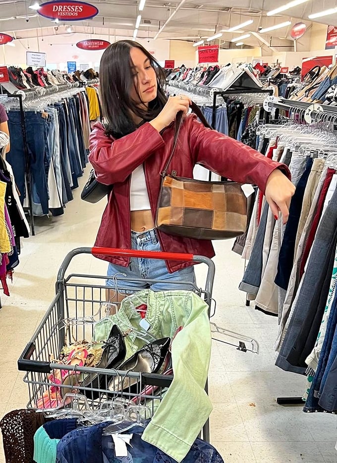The thrill of the hunt in action – a shopper examines a vintage handbag while her cart fills with fashion gold.