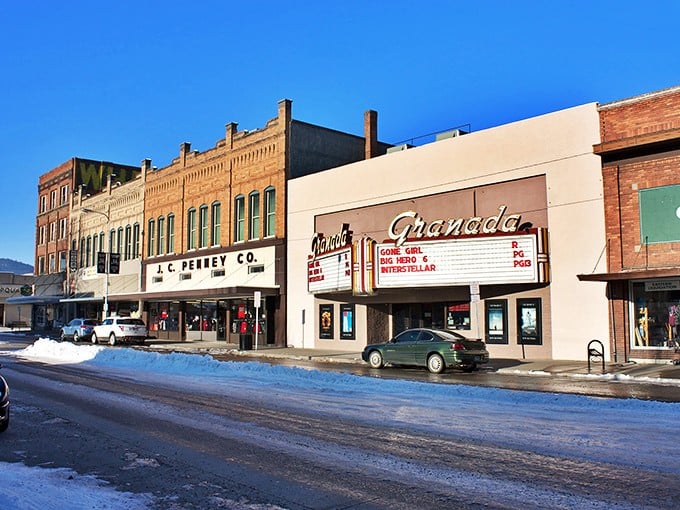 A charming small-town street scene featuring a vintage J.C. Penney storefront and the historic Granada Theater, set against a clear winter day.