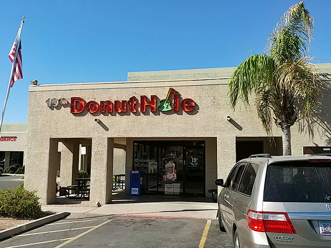 The American flag stands proudly beside 19th Donut Hole, where patriotism and pastries come together in delicious harmony.
