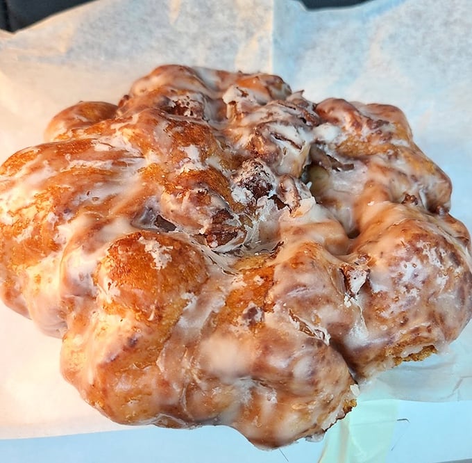 The apple fritter—that magnificent, irregular rebel of the donut world—glistening with glaze and refusing to conform to circular expectations.