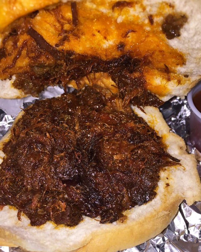 This BBQ pork sandwich isn't messing around—dark, rich sauce clinging to tender shredded meat on that perfectly steamed bun. Napkins required, regrets impossible.