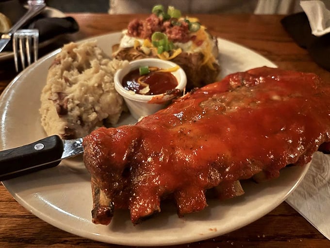 These ribs aren't falling off the bone—they're voluntarily leaping into flavor paradise alongside mashed potatoes and a loaded baked potato.