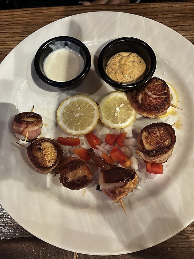 Bacon-wrapped scallops: where sea meets swine in perfect harmony. These little flavor bombs come with dipping sauces that'll have you plotting your next visit.