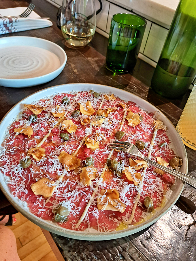 The star of the show—beef carpaccio swimming in golden olive oil with hazelnuts scattered like treasure. Proof that sometimes the best cooking involves no cooking at all.