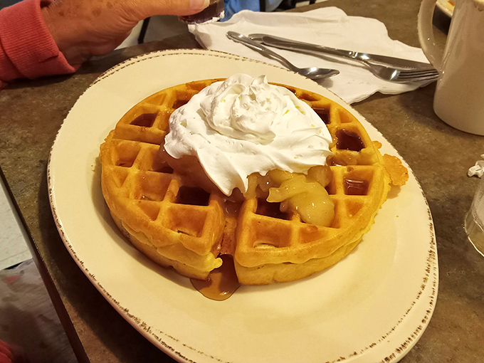 This Belgian waffle isn't just breakfast—it's architecture with purpose, crowned with a dollop of whipped cream that means business.