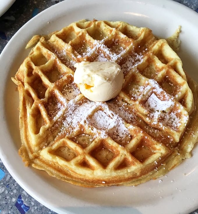 This Belgian waffle isn't just breakfast—it's architecture. Perfectly formed squares cradle butter and powdered sugar in a morning masterpiece worth waking up for.