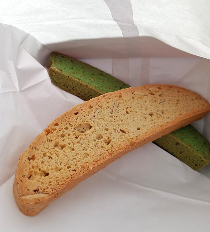 Traditional biscotti—one beige, one green—waiting to be dunked. These twice-baked treasures are the perfect coffee's companion for thoughtful conversations.