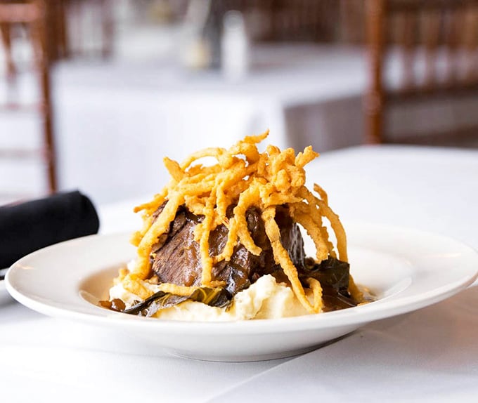 These braised short ribs don't just fall off the bone—they practically leap onto your fork, crowned with crispy onion straws like a royal wearing delicious jewelry.