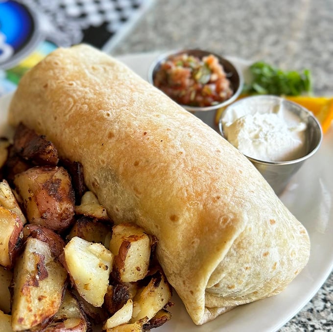 This breakfast burrito isn't just a meal, it's an architectural achievement, flanked by perfectly seasoned potatoes and fresh salsa.