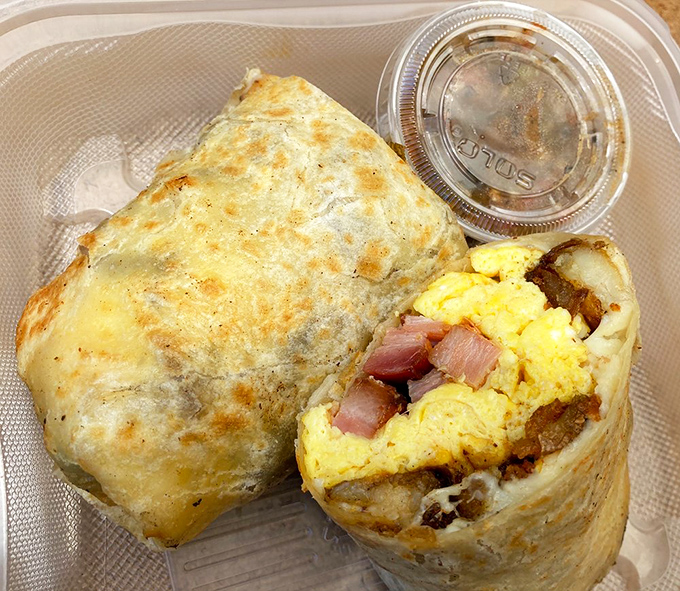 Breakfast burritos should always look like this – a golden package revealing scrambled eggs, potatoes, and thick-cut bacon that makes morning meetings completely optional.