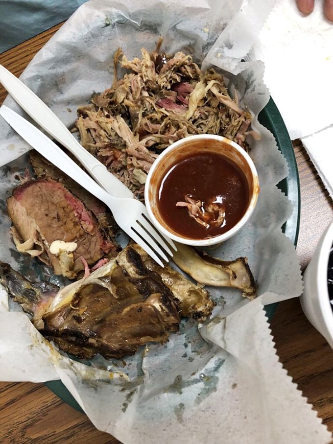 The barbecue trinity—brisket, pulled pork, and ribs—arranged on butcher paper like the culinary equivalent of a Renaissance painting.