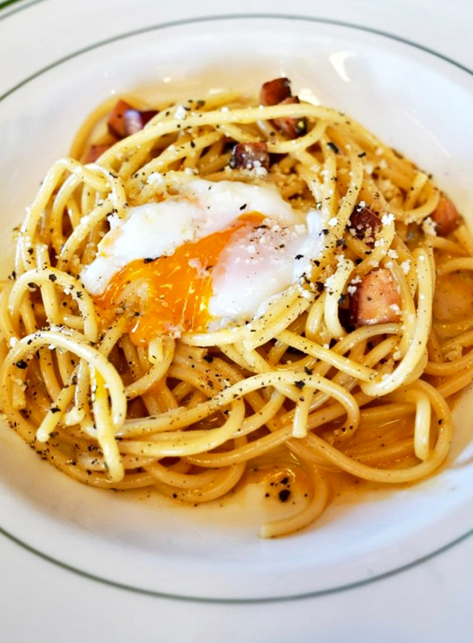 The Bucatini Carbonara with its perfectly runny egg transforms pasta into poetry—swordfish "bacon" adding a brilliant maritime twist to an Italian classic.