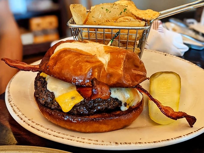 A burger that requires both hands and a strategy—crispy bacon hanging off the edges like it's making a break for freedom.