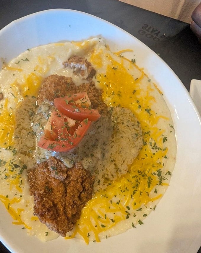 Southern comfort in a bowl—golden fried catfish nestled in creamy, cheesy grits with fresh tomato adding a pop of color and acidity.