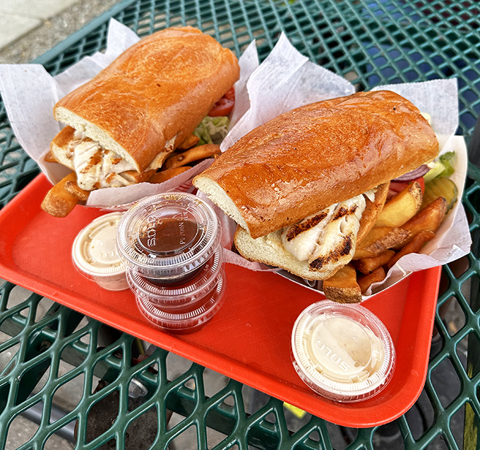 Sandwich architecture at its finest – crusty bread cradling perfectly grilled fish, with fries standing by for the inevitable dipping emergency.