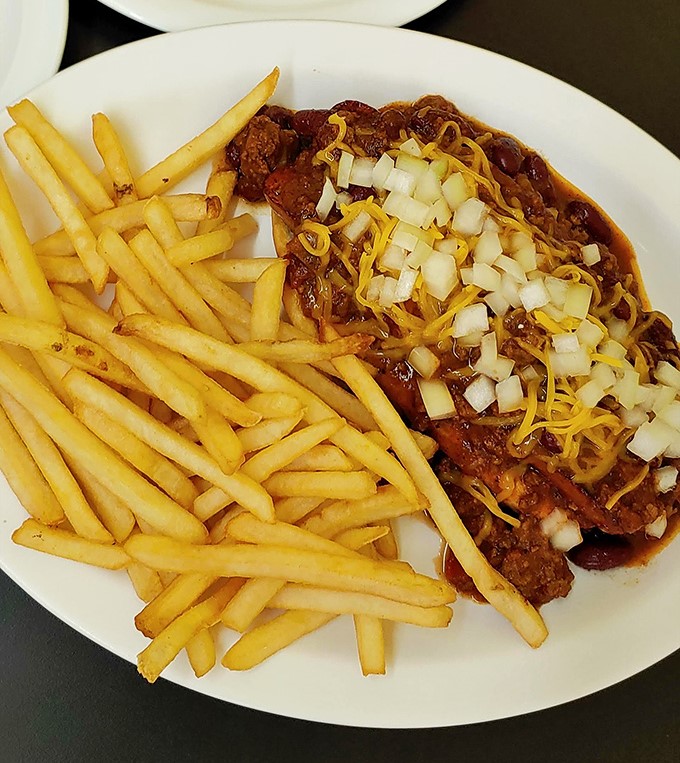 Chili that doesn't hide behind pretension, topped with diced onions and shredded cheese – comfort food that demands both napkins and respect.