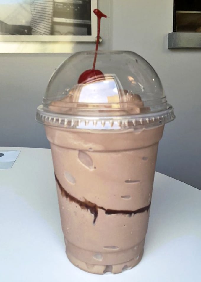 Chocolate shake nirvana awaits beneath that dome lid—thick enough for spoon archaeology but still technically sippable through a straw.