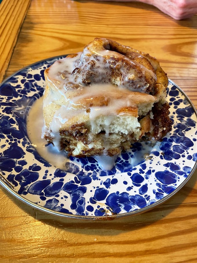 This cinnamon roll isn't just dessert pretending to be breakfast—it's a gooey, glazed monument to morning indulgence on a blue-speckled plate.