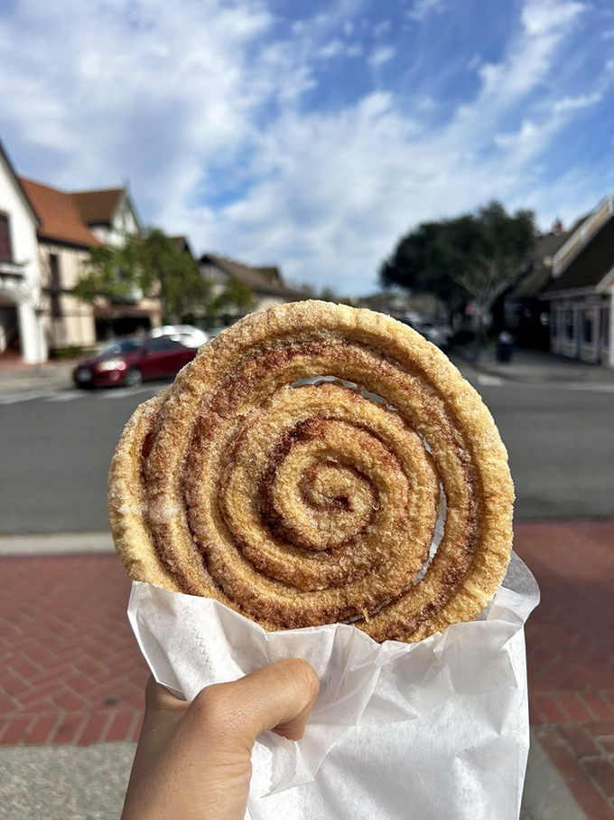 Cinnamon and sugar spiral hypnotically in this hand-held wonder, turning an ordinary Solvang stroll into a transcendent sidewalk experience.