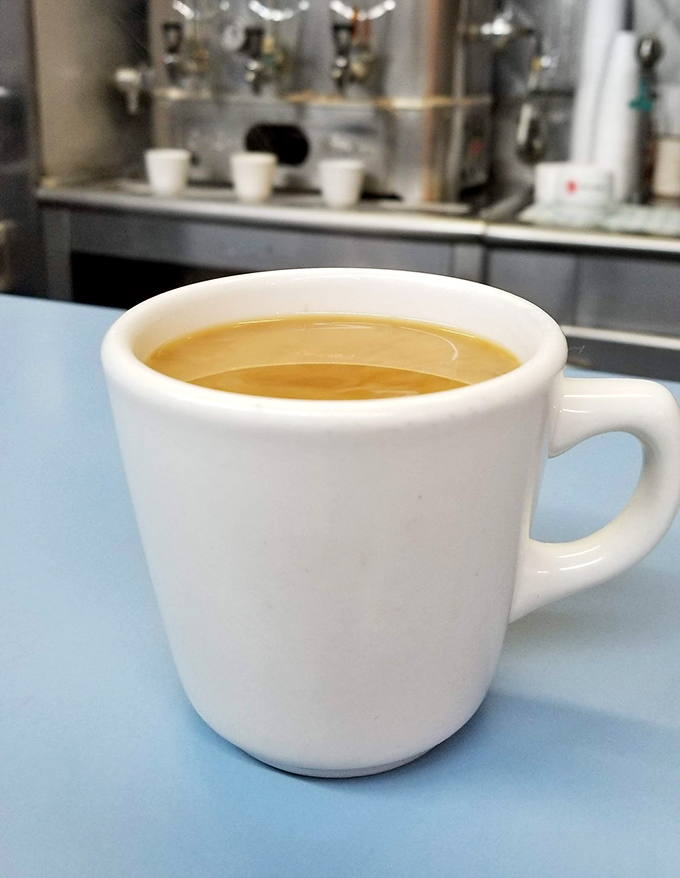 Coffee served in sturdy white mugs against the blue countertop—no fancy latte art needed when you're washing down the best ham sandwich in Michigan.