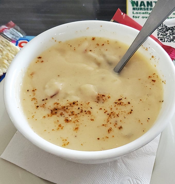 The legendary crab soup in all its glory—creamy, speckled with Old Bay, and hiding tender lumps of crab like buried treasure in every spoonful.