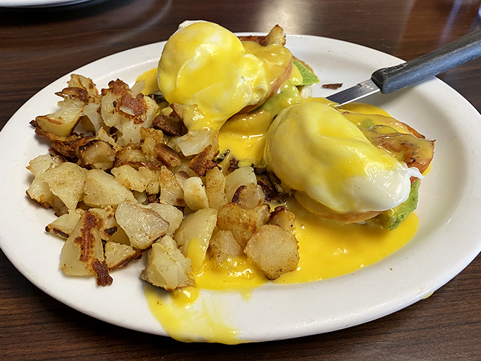 Eggs Benedict done right – that hollandaise cascades down like a yellow waterfall of happiness, making every bite a treasure hunt.