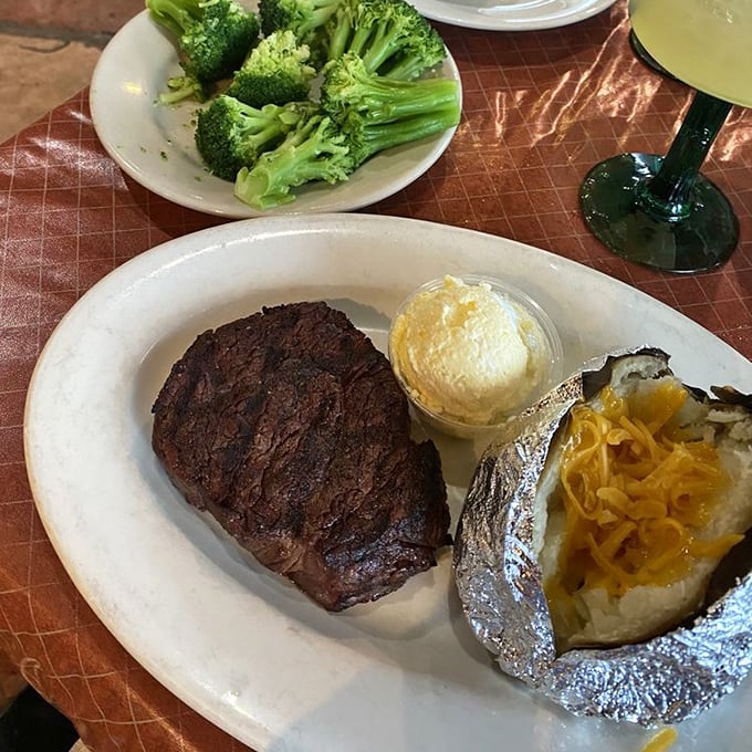 The filet mignon arrives like a distinguished gentleman—perfectly dressed in a char tuxedo with a baked potato sidekick sporting cheesy bling.
