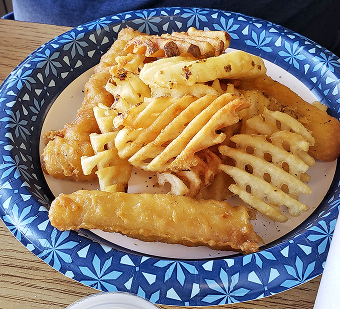 Crispy fish and waffle fries on a blue-patterned plate—proof that while chicken rules the roost, the supporting cast deserves applause too.