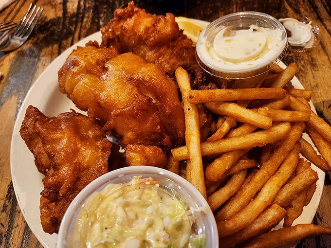 Golden-battered fish that shatters like delicate glass when your fork touches it. This isn't just fish and chips – it's edible sunshine on a plate.