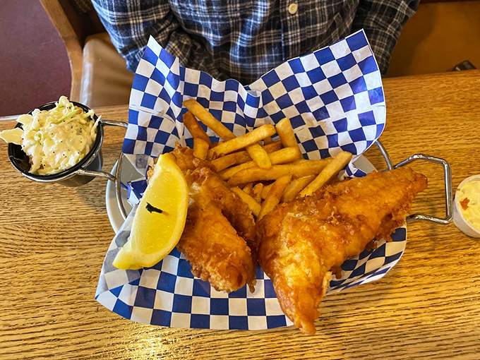 Fish and chips served in a blue-checkered paper boat—because even seafood deserves a cute outfit before meeting its delicious demise.