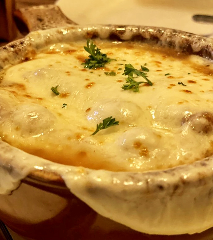 French onion soup that's had a proper education—a bubbling masterclass in patience where cheese stretches like your uncle's fishing stories.