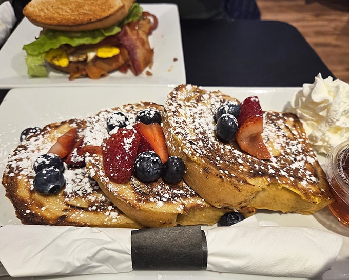 French toast that makes you question all other breakfast decisions – golden challah adorned with fresh berries and a snowfall of powdered sugar.