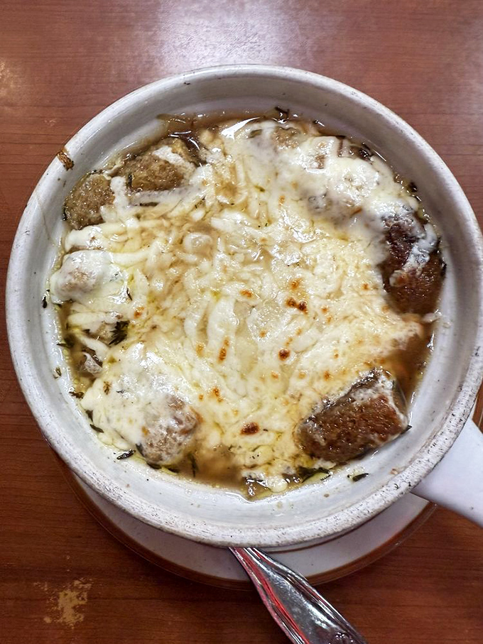 French onion soup done right – a bubbling cauldron of savory broth where croutons and cheese have united in melty matrimony. Spoon-breaking good.