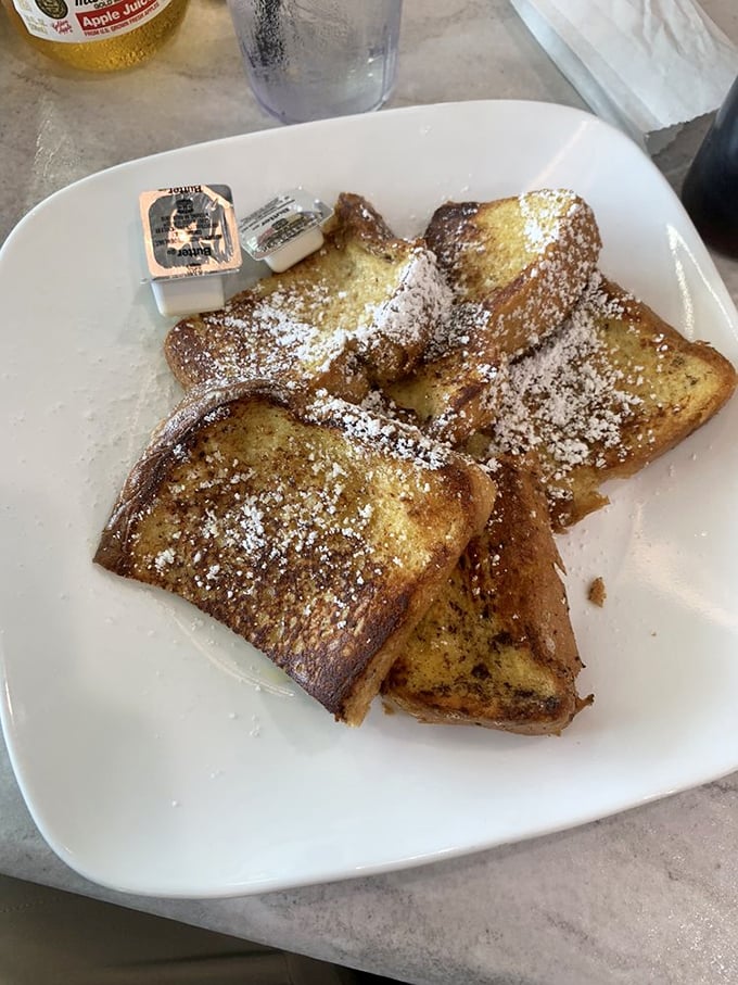 The French toast that launched a thousand return visits—golden, crispy edges giving way to custardy centers under a snowy dusting of powdered sugar.