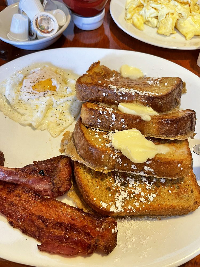 French toast stacked higher than your weekend expectations. Those butter pats aren't melting—they're surrendering to the inevitable deliciousness.