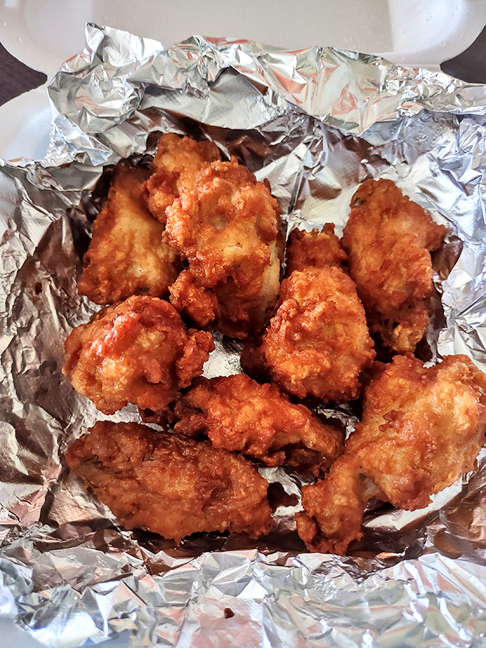 Fried chicken wings nestled in foil—crispy, golden-brown armor protecting juicy meat within. Simple pleasures that need no explanation.